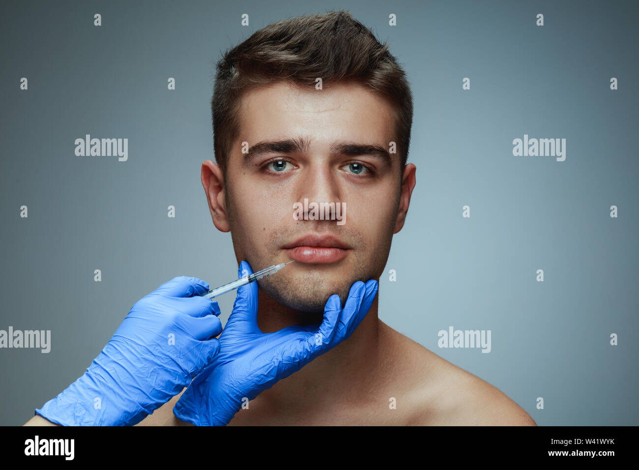 Close-up portrait of young man isolated on grey studio background ...