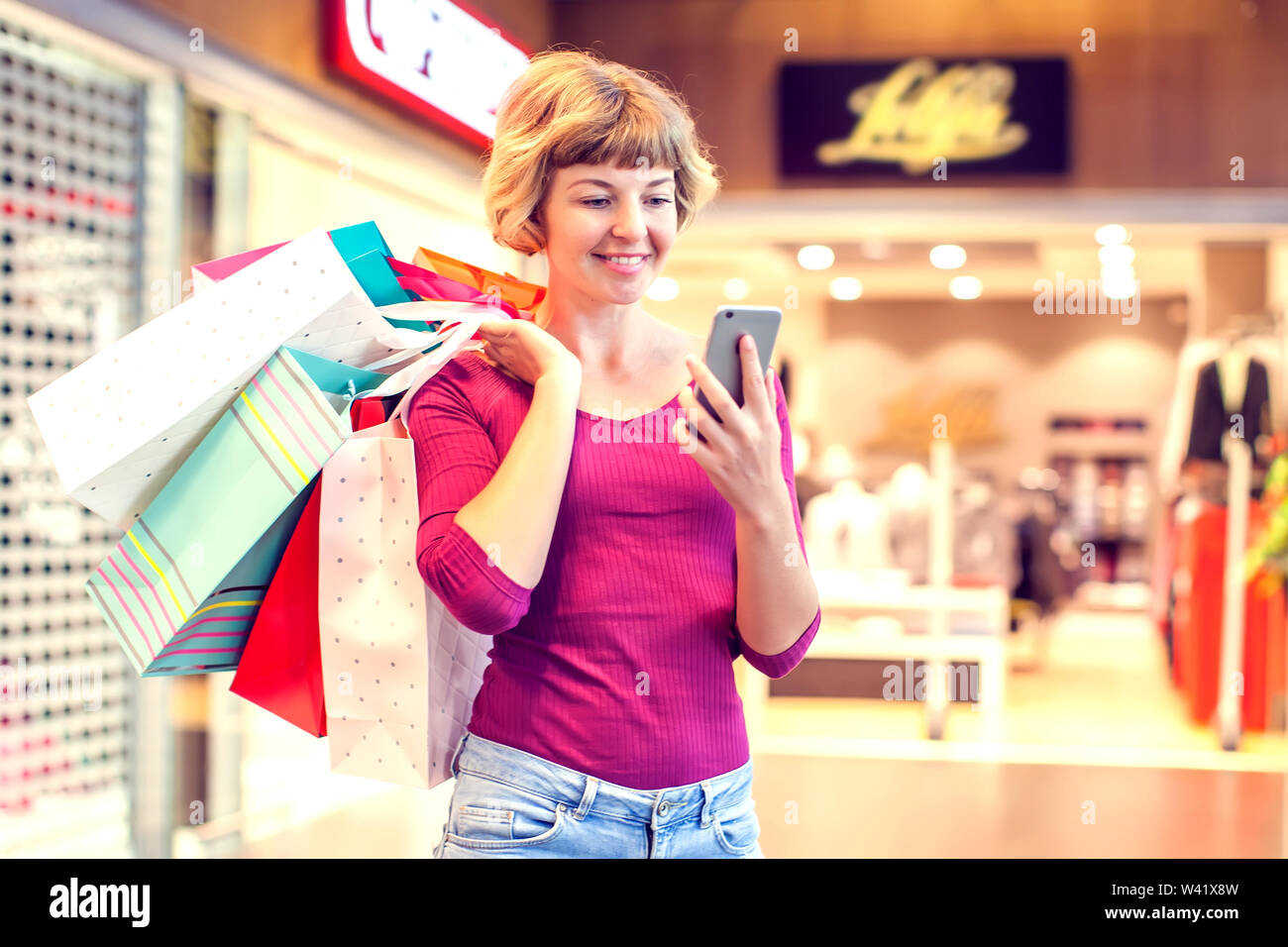 Female customer with mobile phone and shopping bags in the mall Stock ...