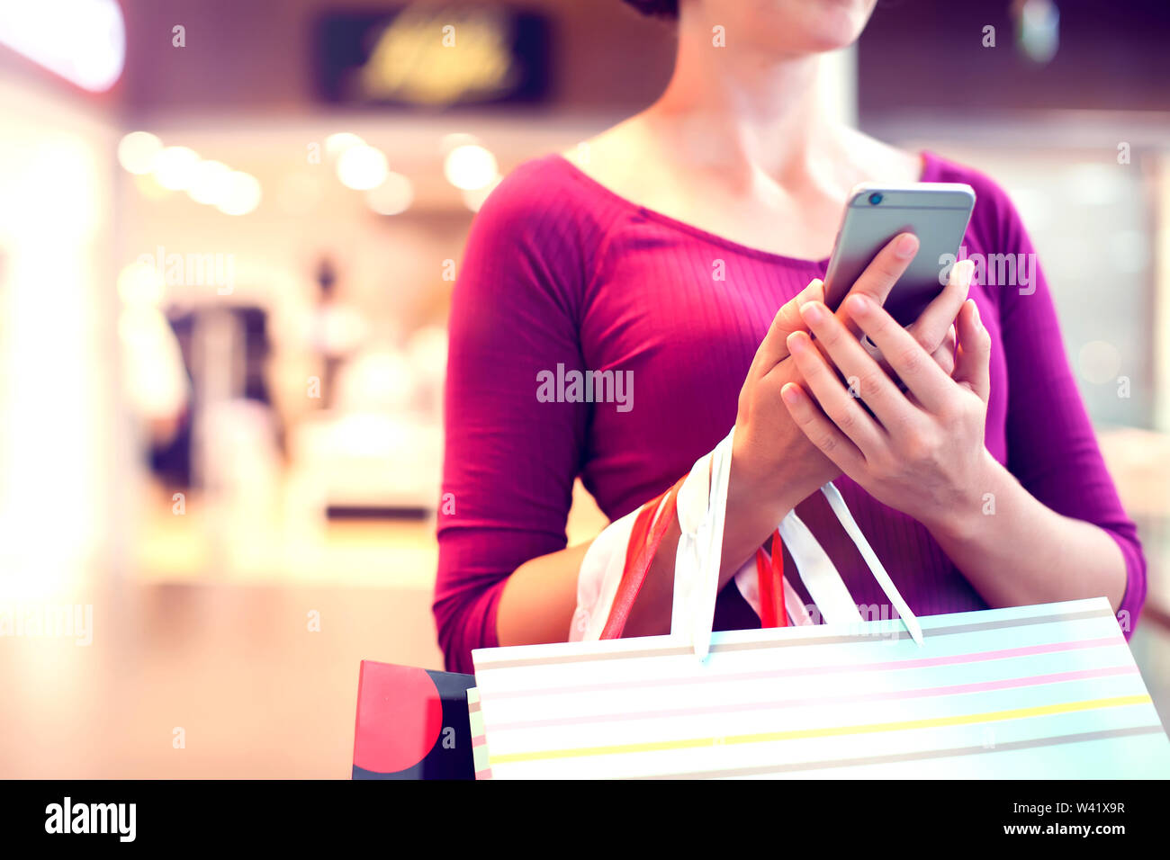 Female customer with mobilephone and shopping bags in the mall Stock ...
