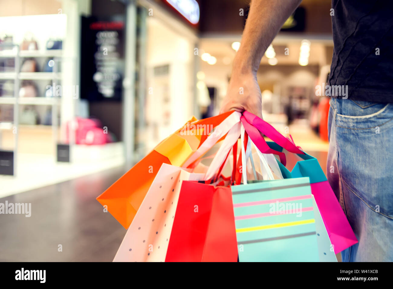 Cropped image of handsome guy with shopping bags doing shopping in the ...