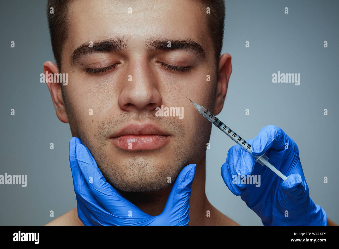 Close-up portrait of young man isolated on grey studio background ...