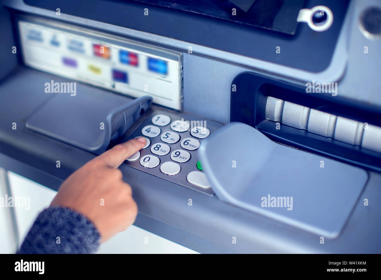 Finance, money, bank and people concept - close up of hand entering pin ...