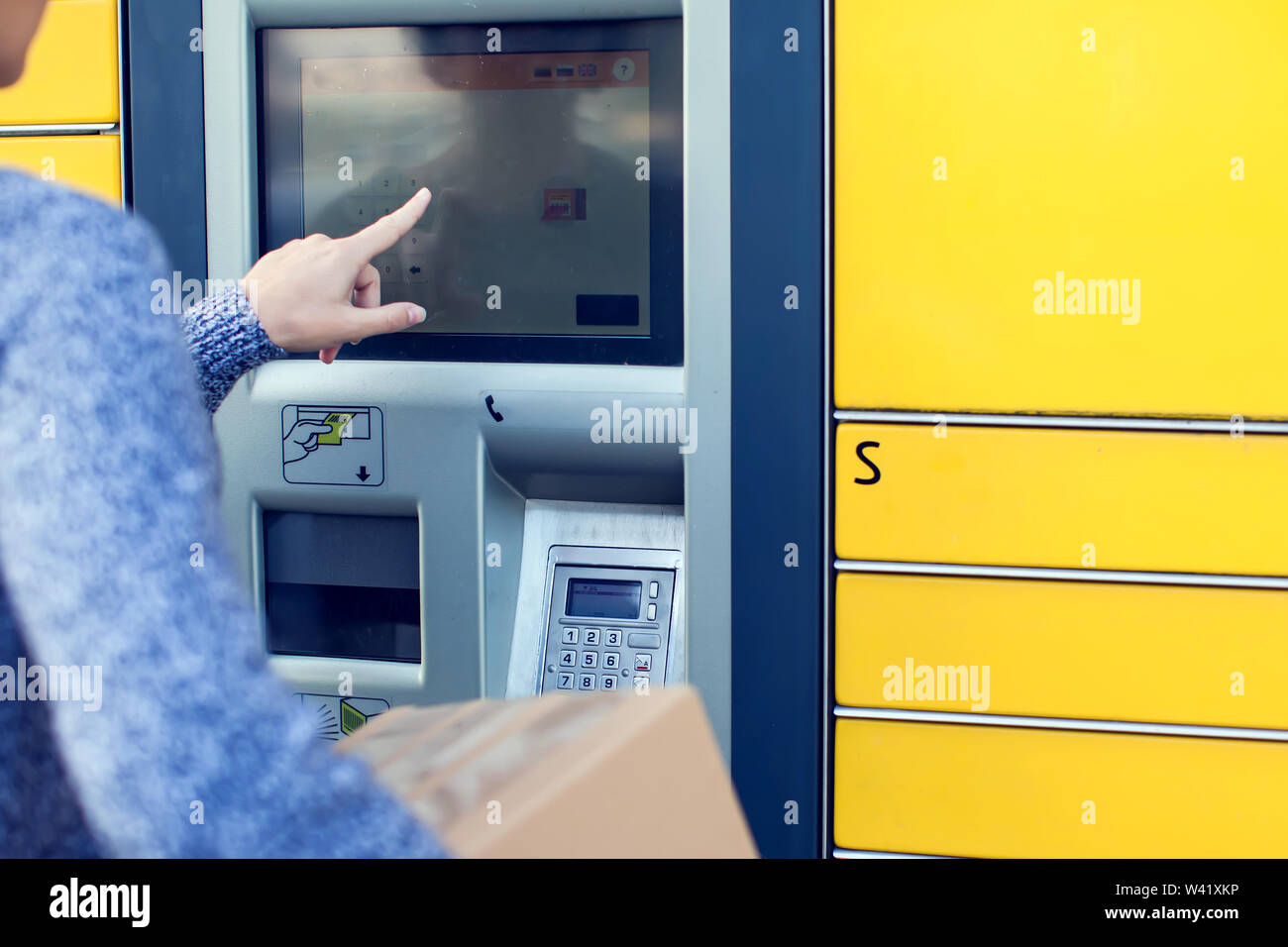 Woman client using automated self service post terminal machine or ...