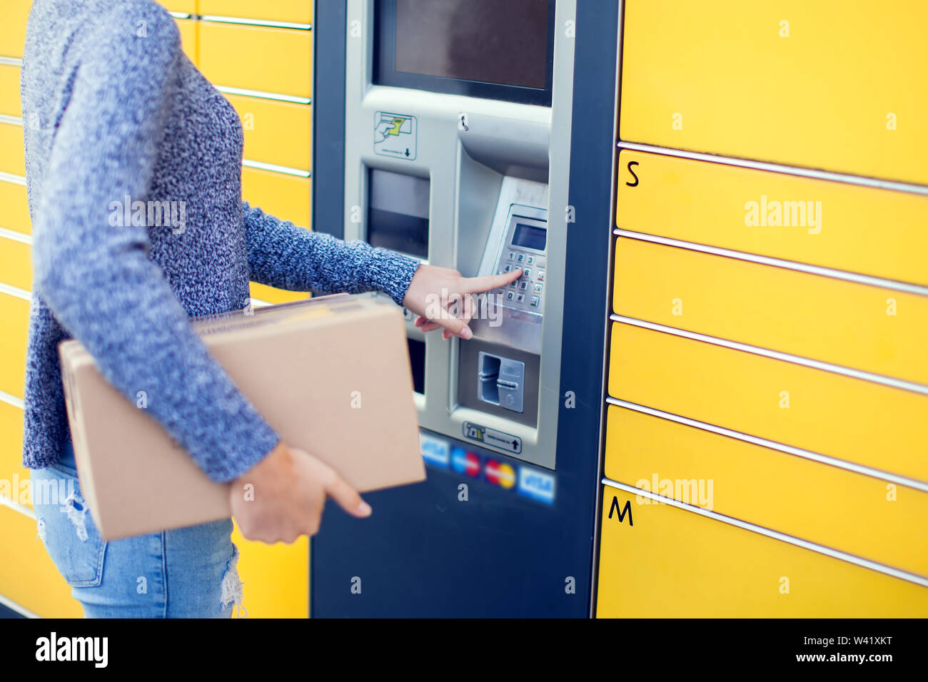 Woman client using automated self service post terminal machine or ...