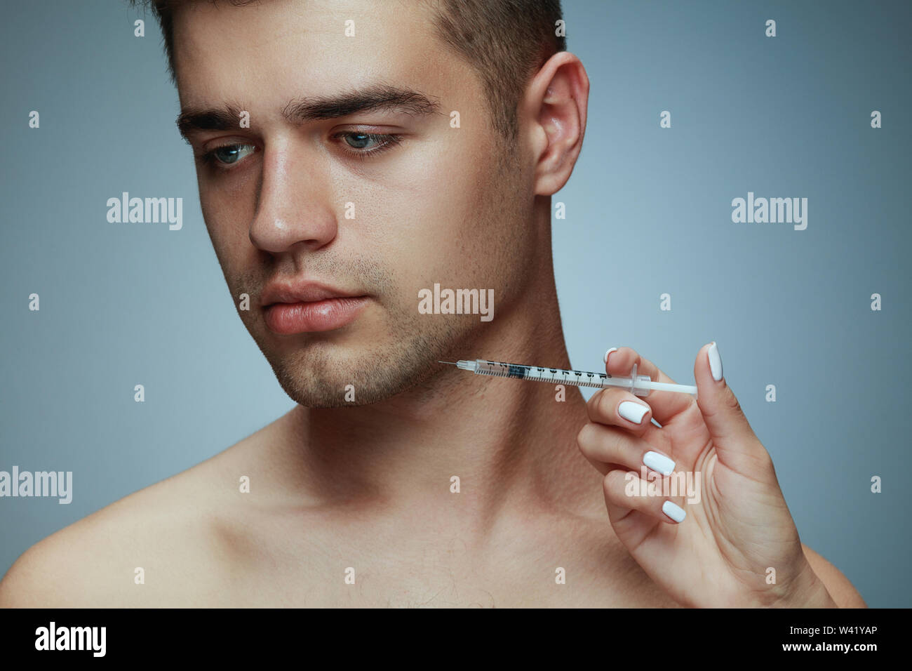 Close-up portrait of young man isolated on grey studio background ...