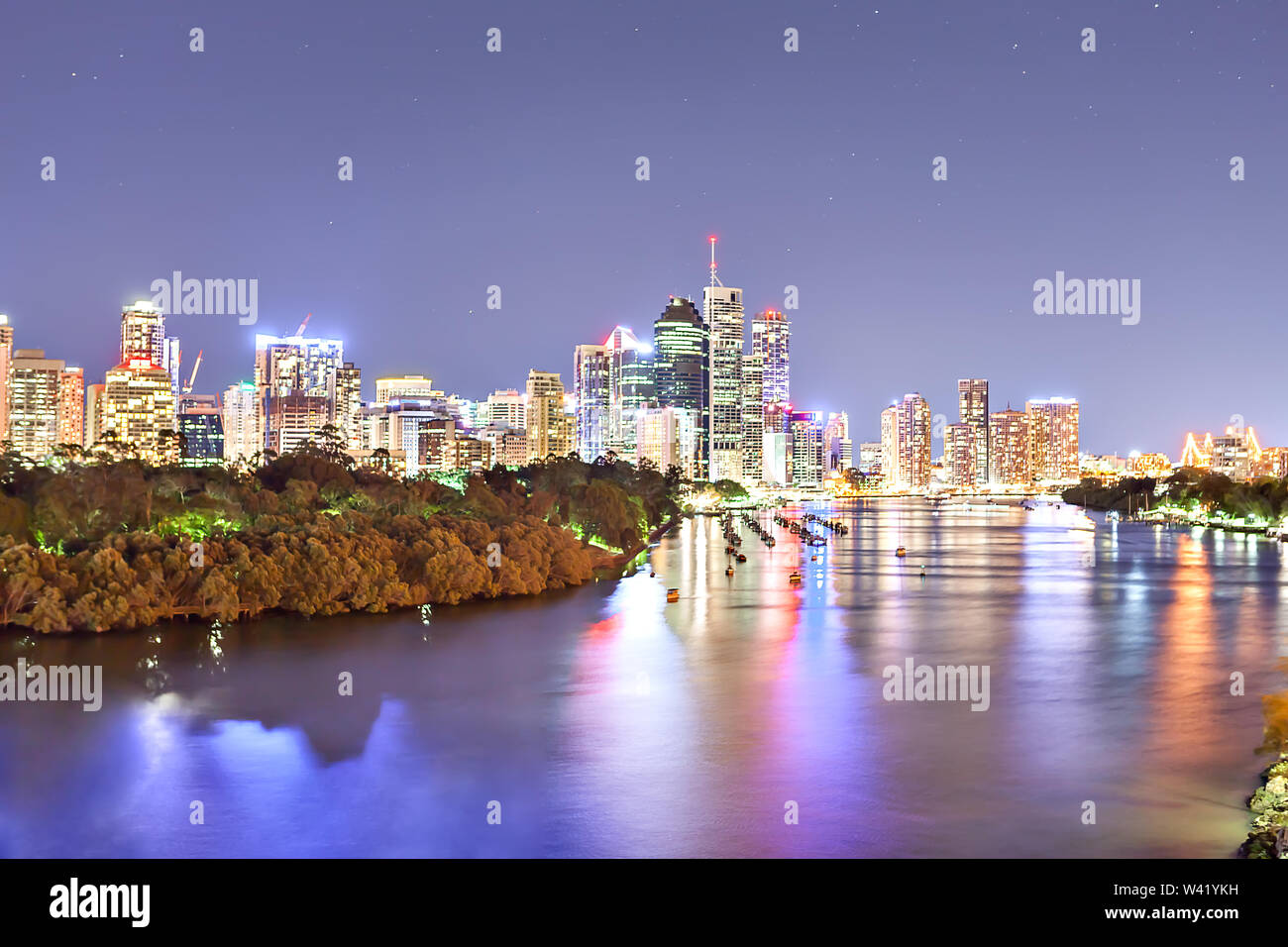 Brisbane City at night beside a river and a wide blue sky showing ...