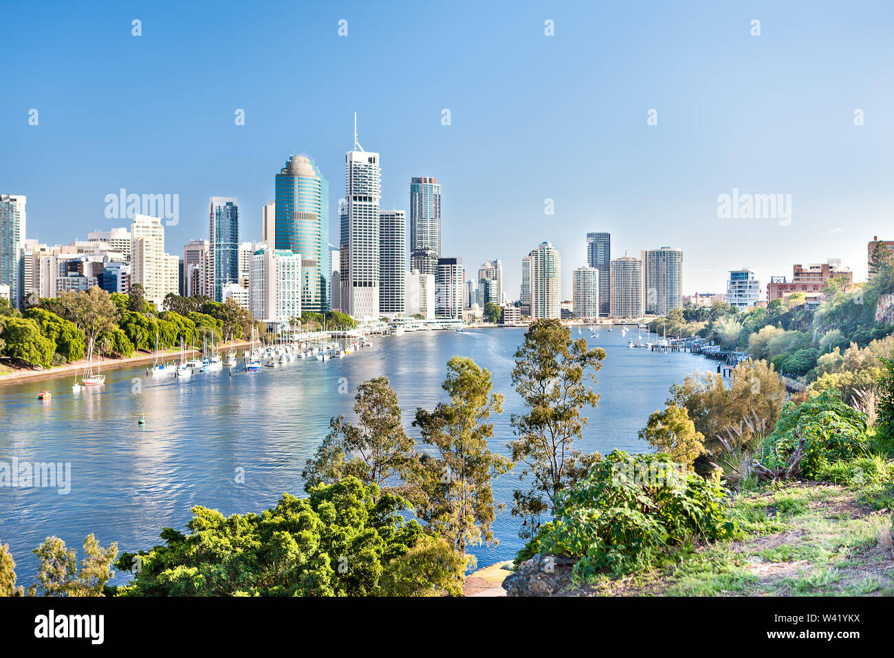 Blue water river surrounded by trees beside a modern cityscape ...