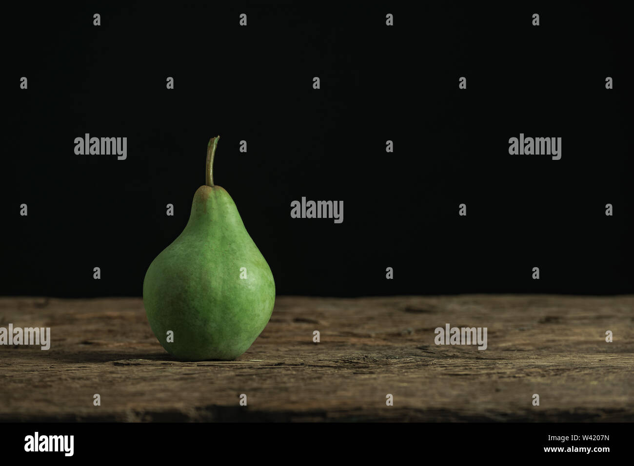 Fresh green peara on a old oak wooden table, beautiful black background ...