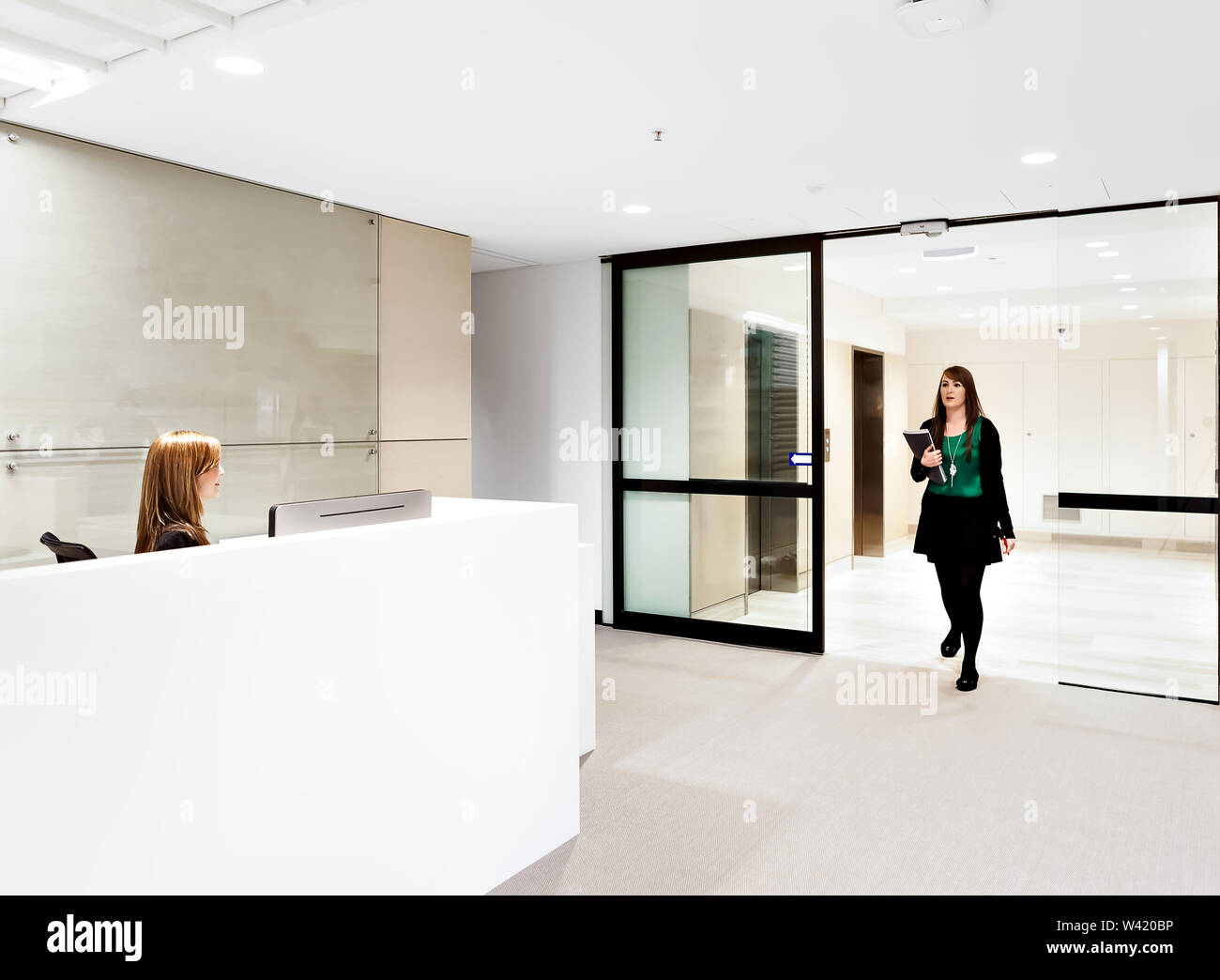 Girl or business woman arriving to a reception passing the glass door ...