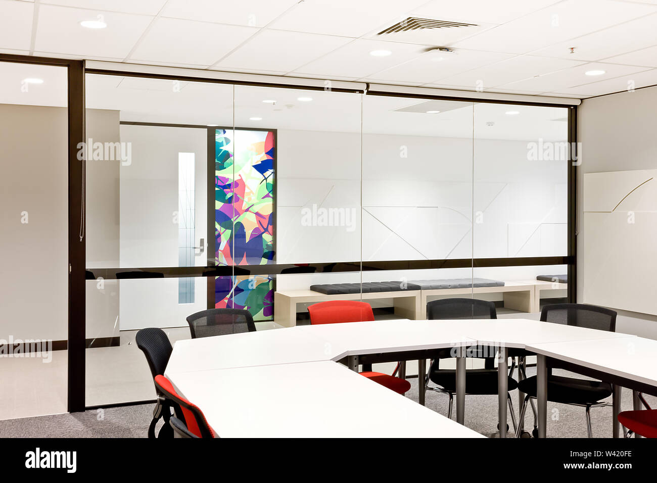 Modern conference room with round white table and chairs next to glass ...