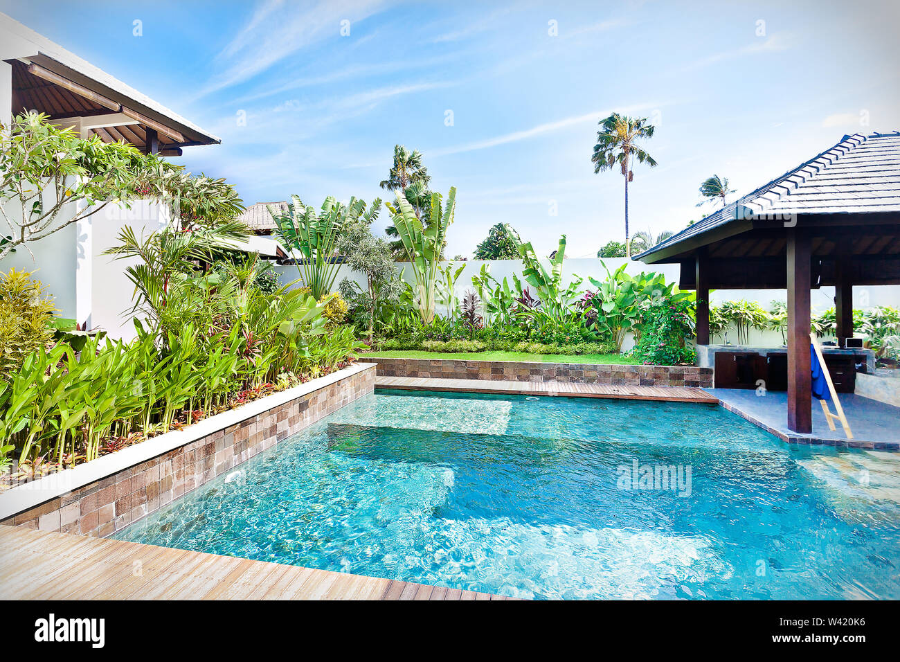 Modern blue water swimming pool with colorful garden including greens ...