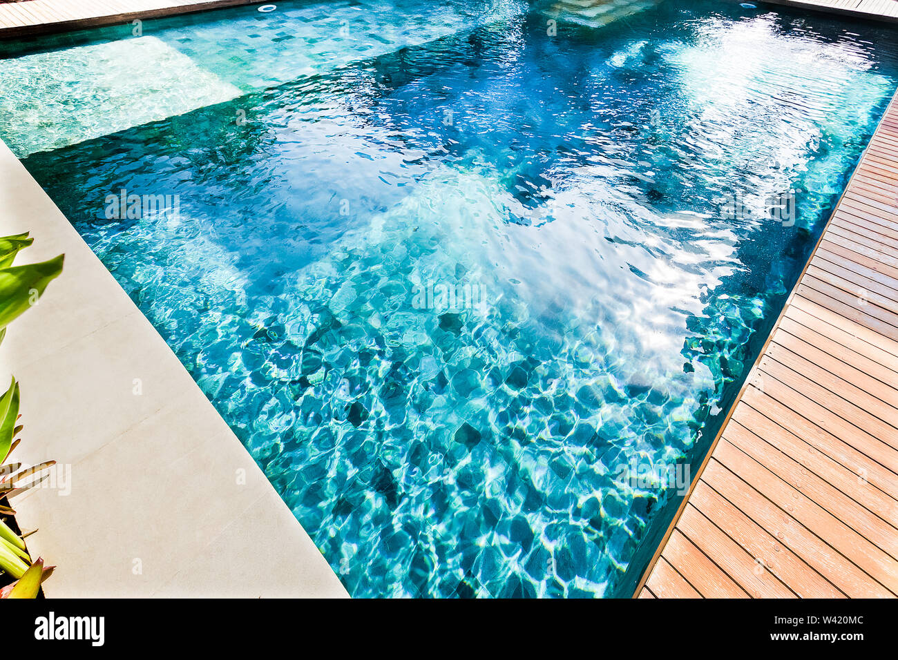 Light blue water swimming pool closeup in a luxury house giving deep ...