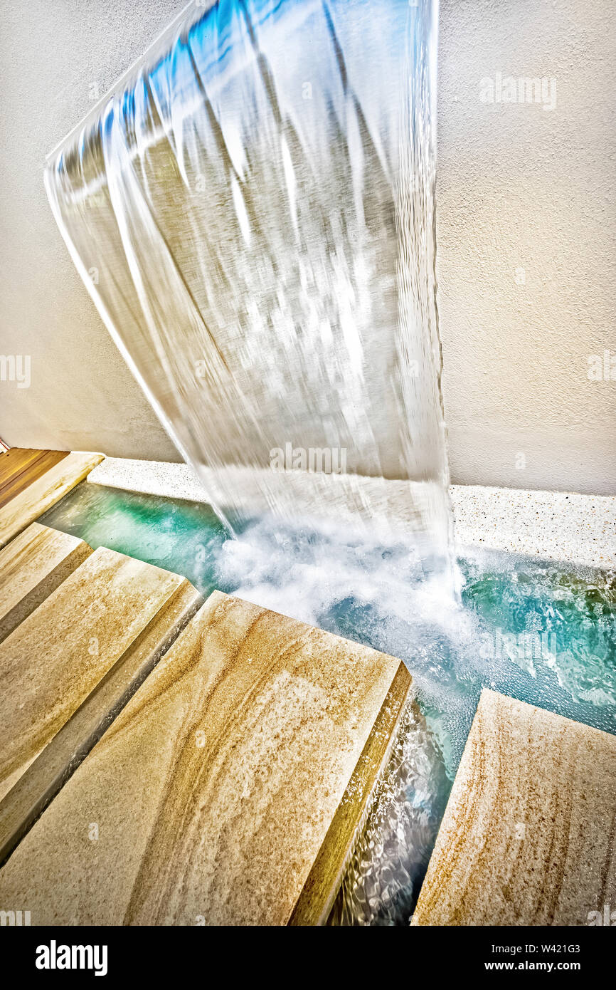 Small wall water fountain with water falling down on the wooden plank ...