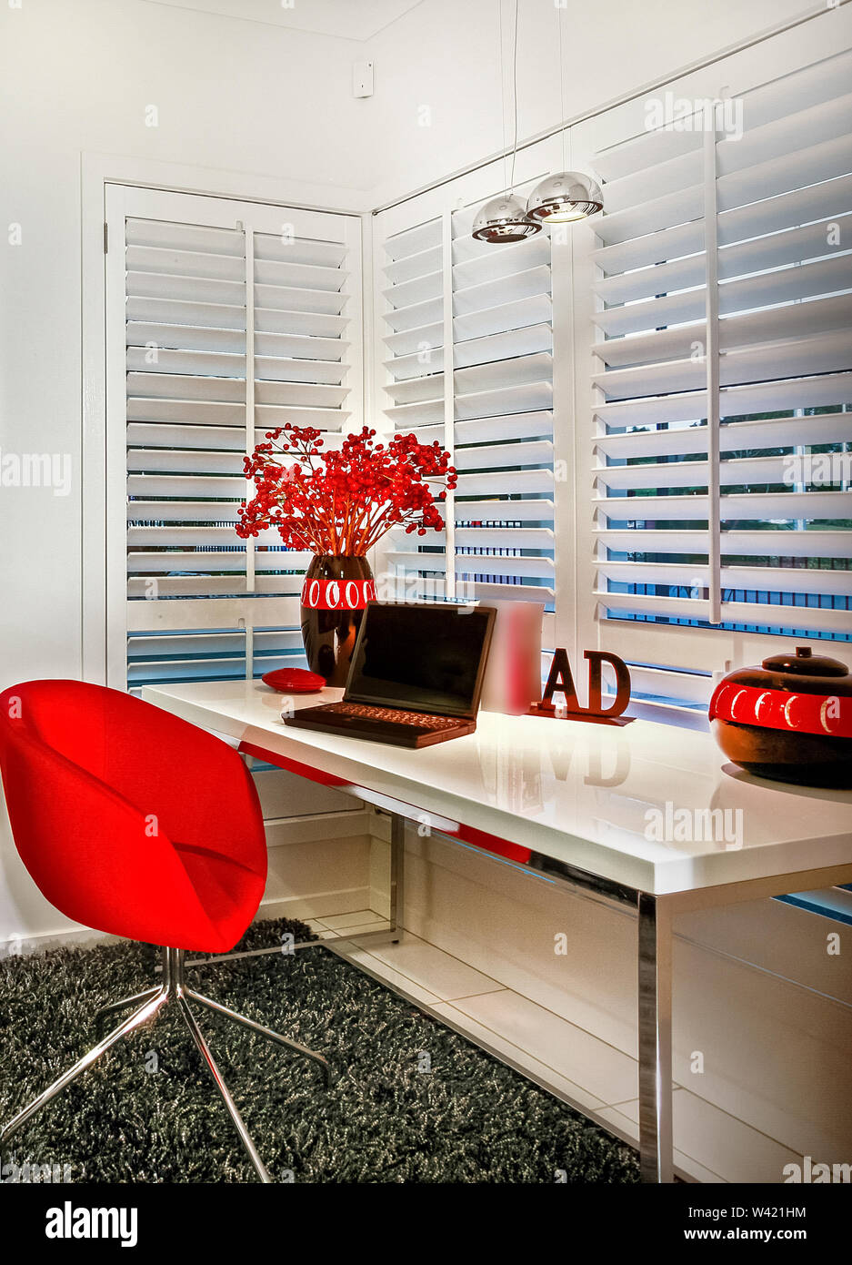 Modern study desk with a laptop, a contemporary chair, and décor items ...