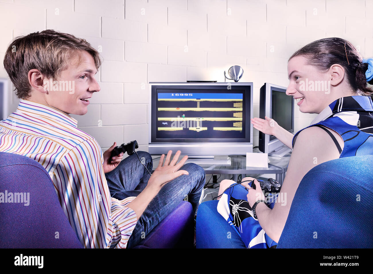 Small kids play games using computers or playstaion and smiling to each ...