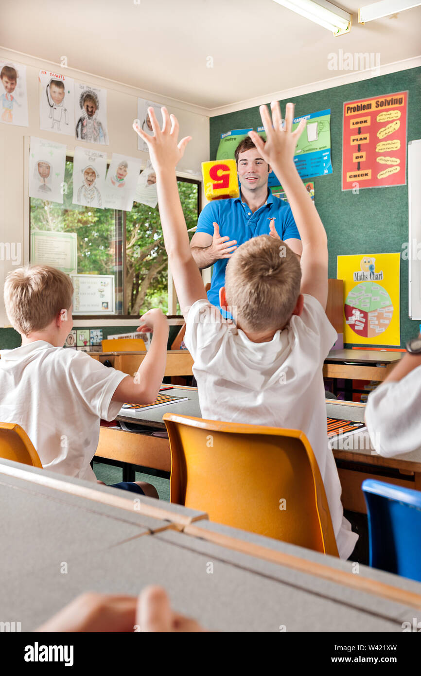 Teacher teaches kids in the classroom using a cube and asking questions ...