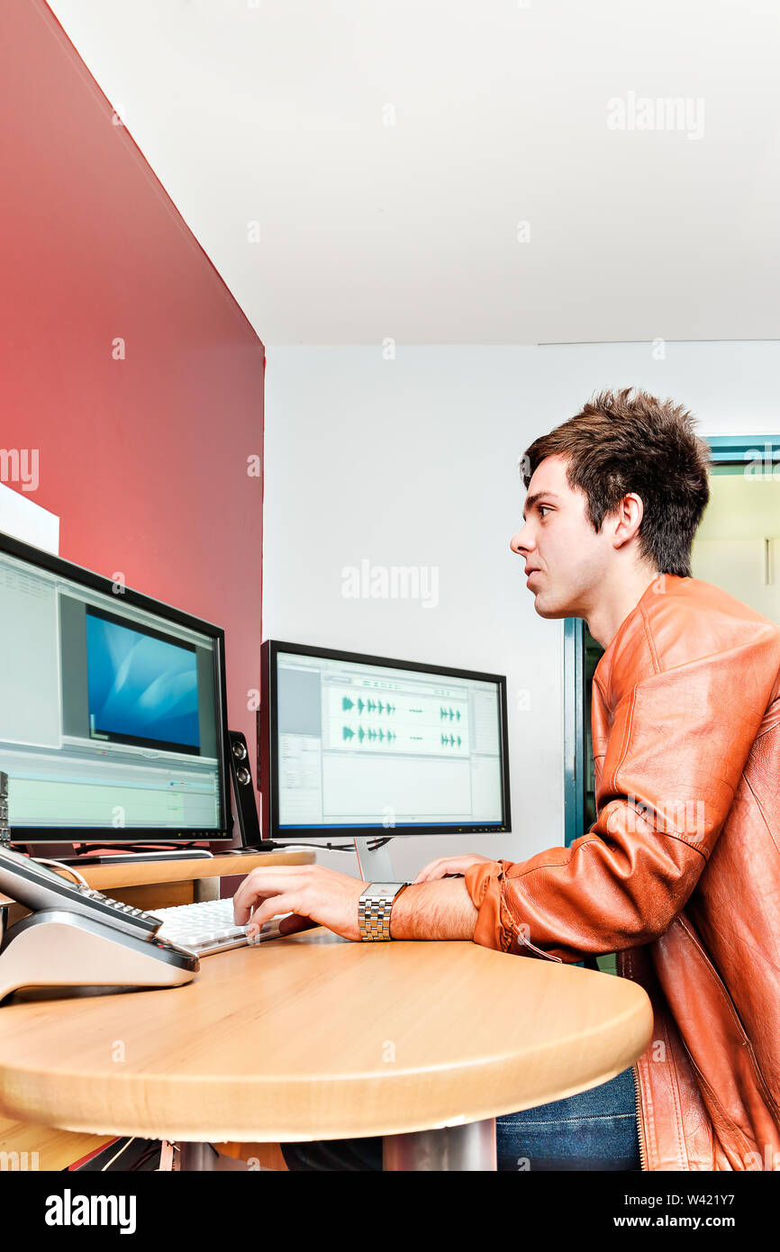 Student working on a computer and focusing the monitors to do editings ...