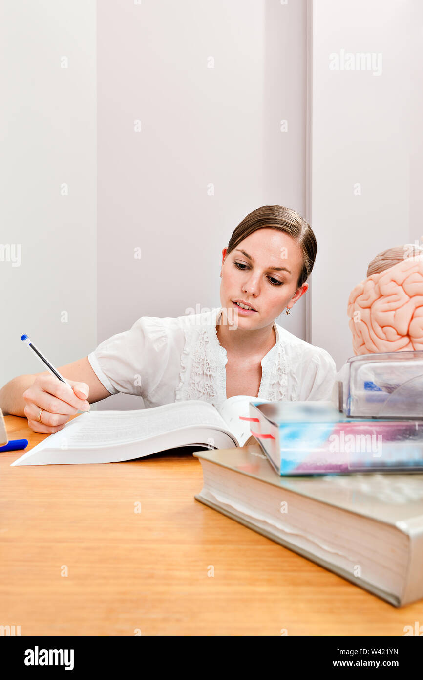 Cute girl writing a book on the table in a classroom Stock Photo - Alamy
