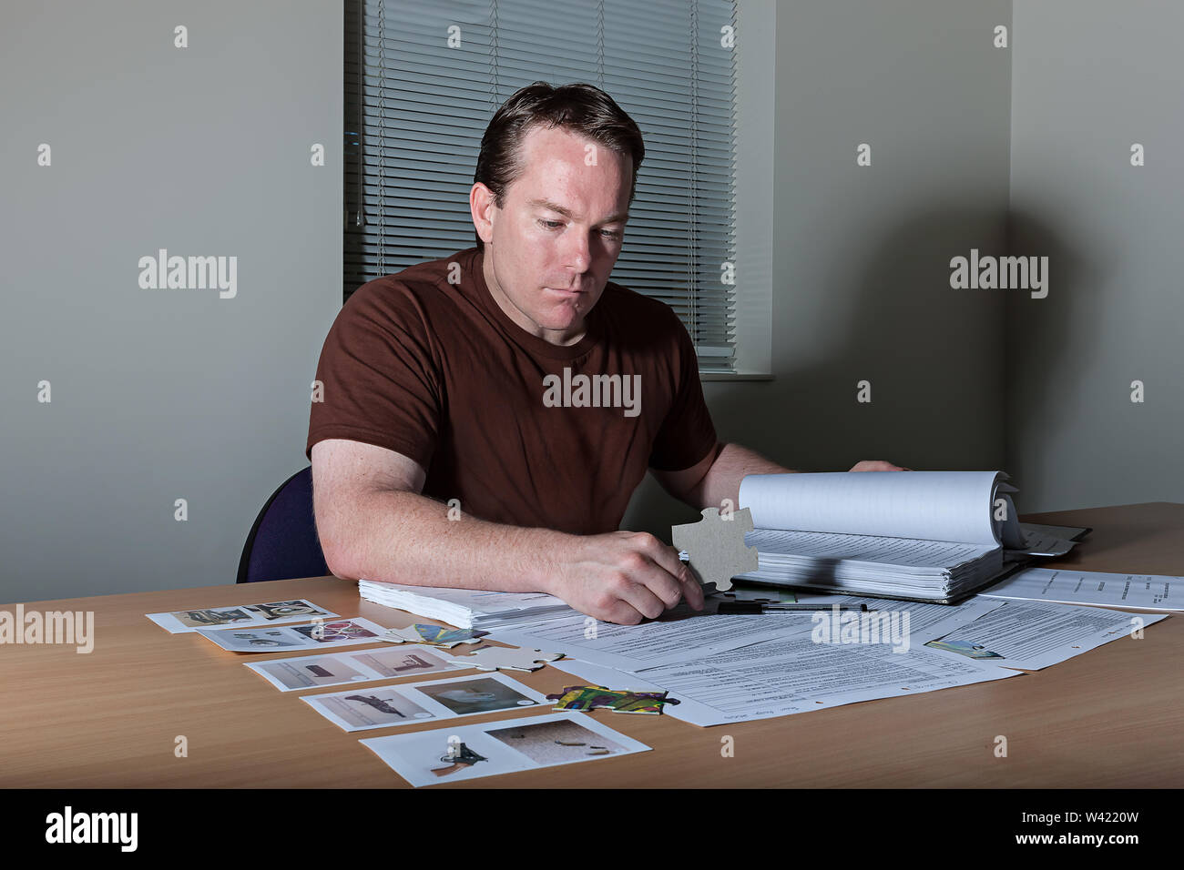 Man trying to solve a puzzle using books and papers Stock Photo - Alamy