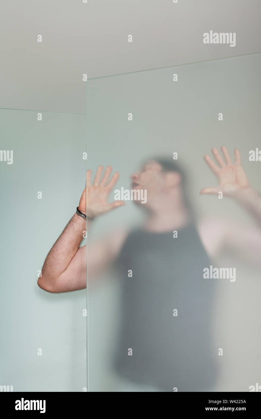 Picture of a man in a black tank pushed against a matte glass door, he ...