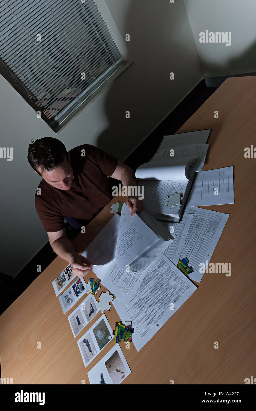 Man is sitting on a chair and reading papers on the wooden table in a ...
