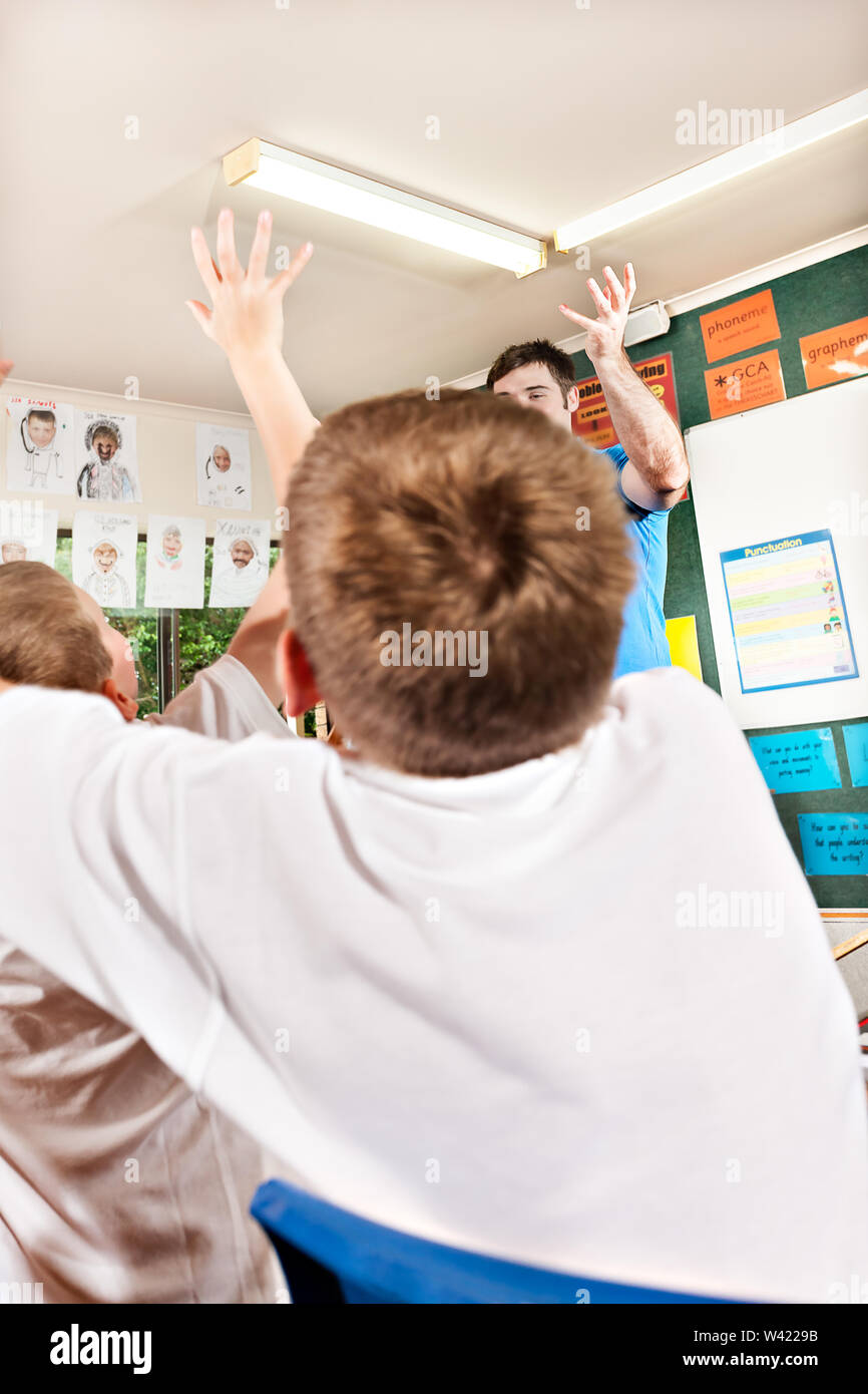 Students hands up in the classroom with the teacher Stock Photo - Alamy