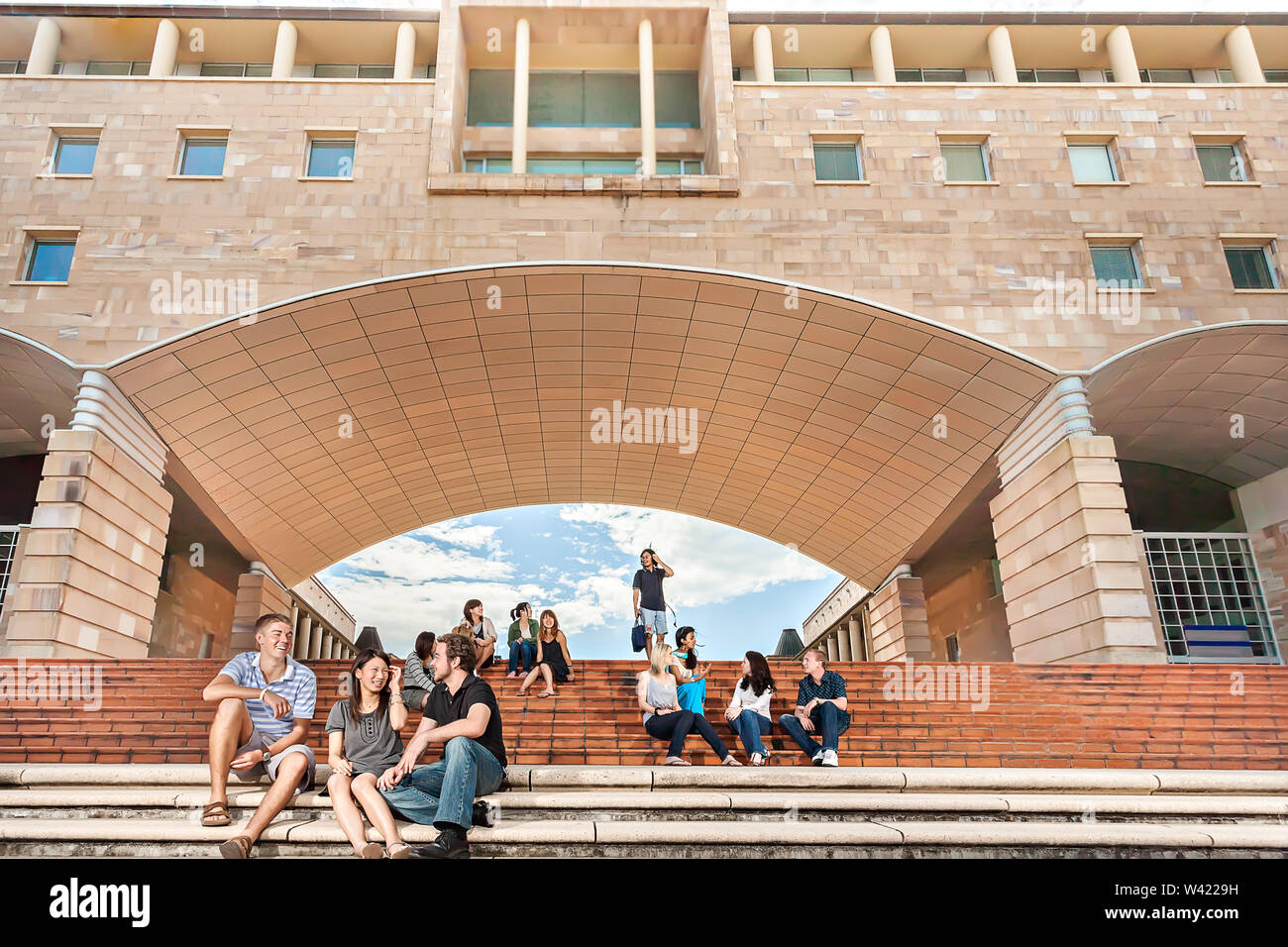 People are sitting on the floor in front of a huge building Stock Photo ...
