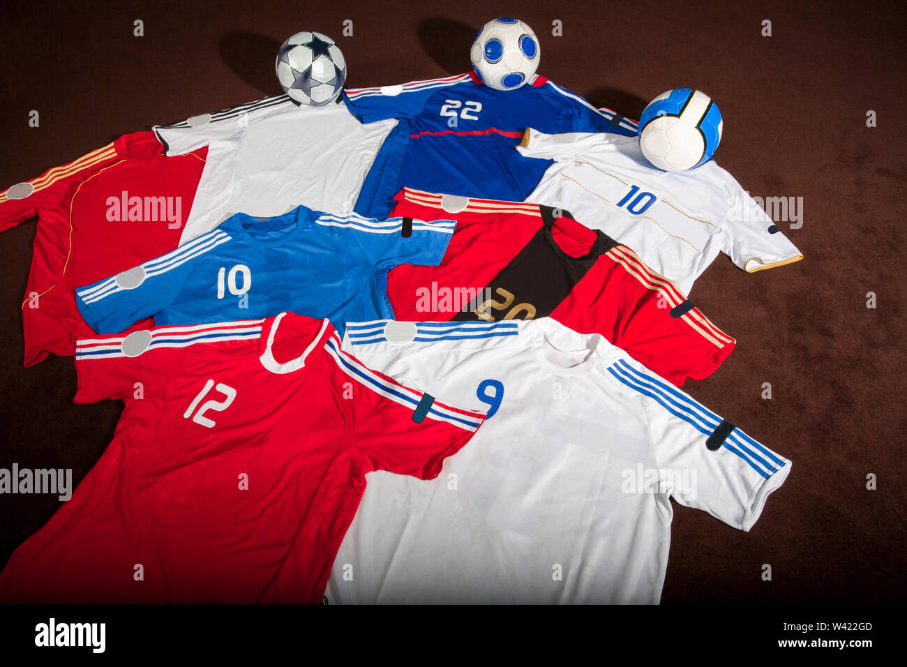 Colorful football team jerseys laid out on the floor, using balls as ...