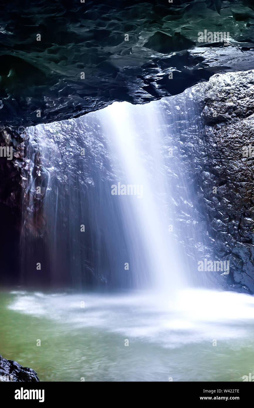 Waterfall blurred and falling down in a dark stone cave and the rocks ...
