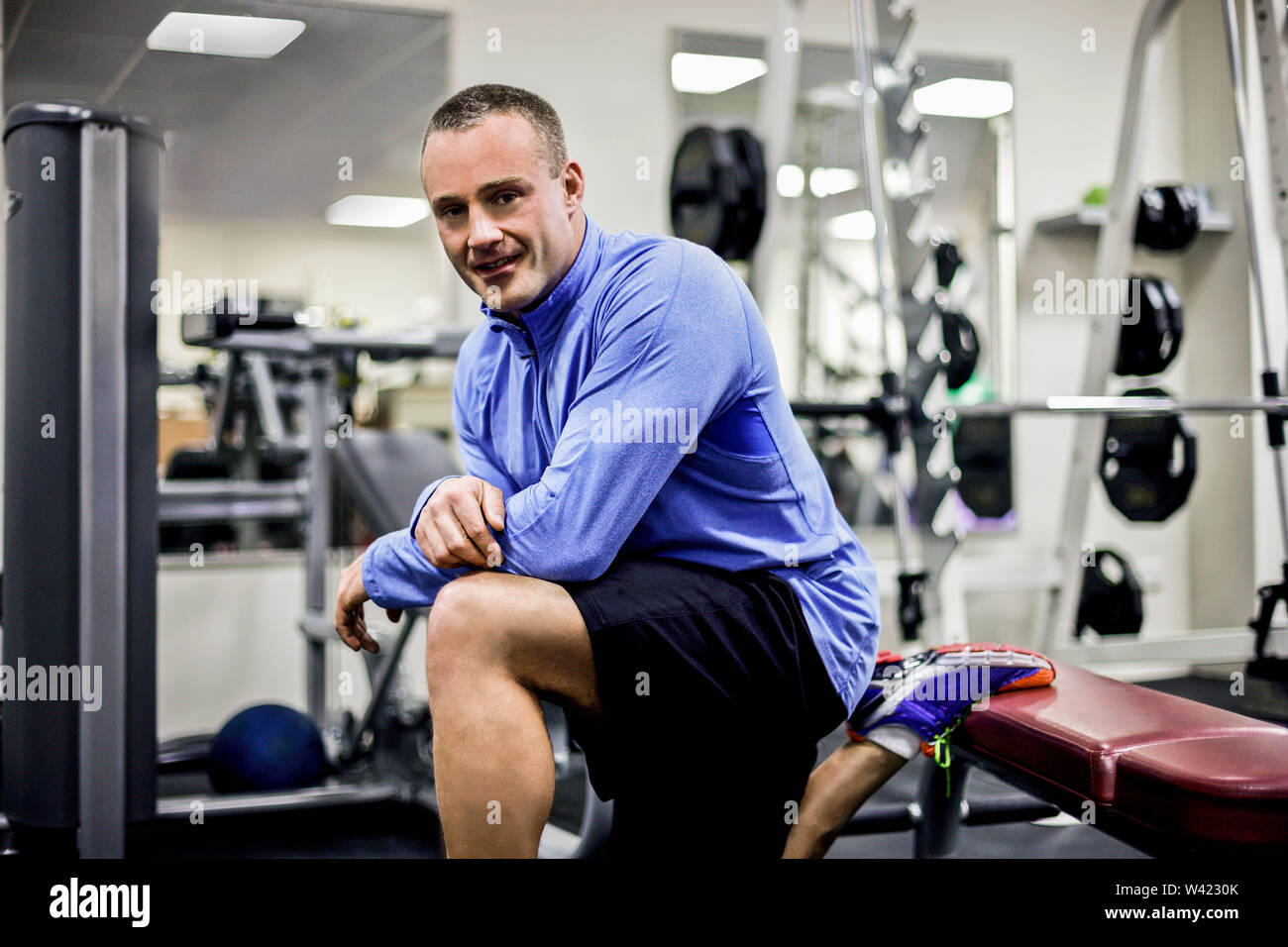 Side view of strong fitness trainer, inside room of a luxury gym, heavy ...