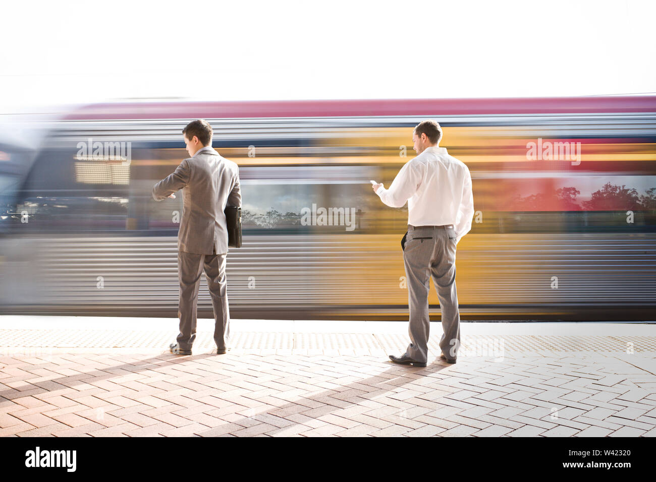 A simple picture of two men standing on a railway platform with passing ...