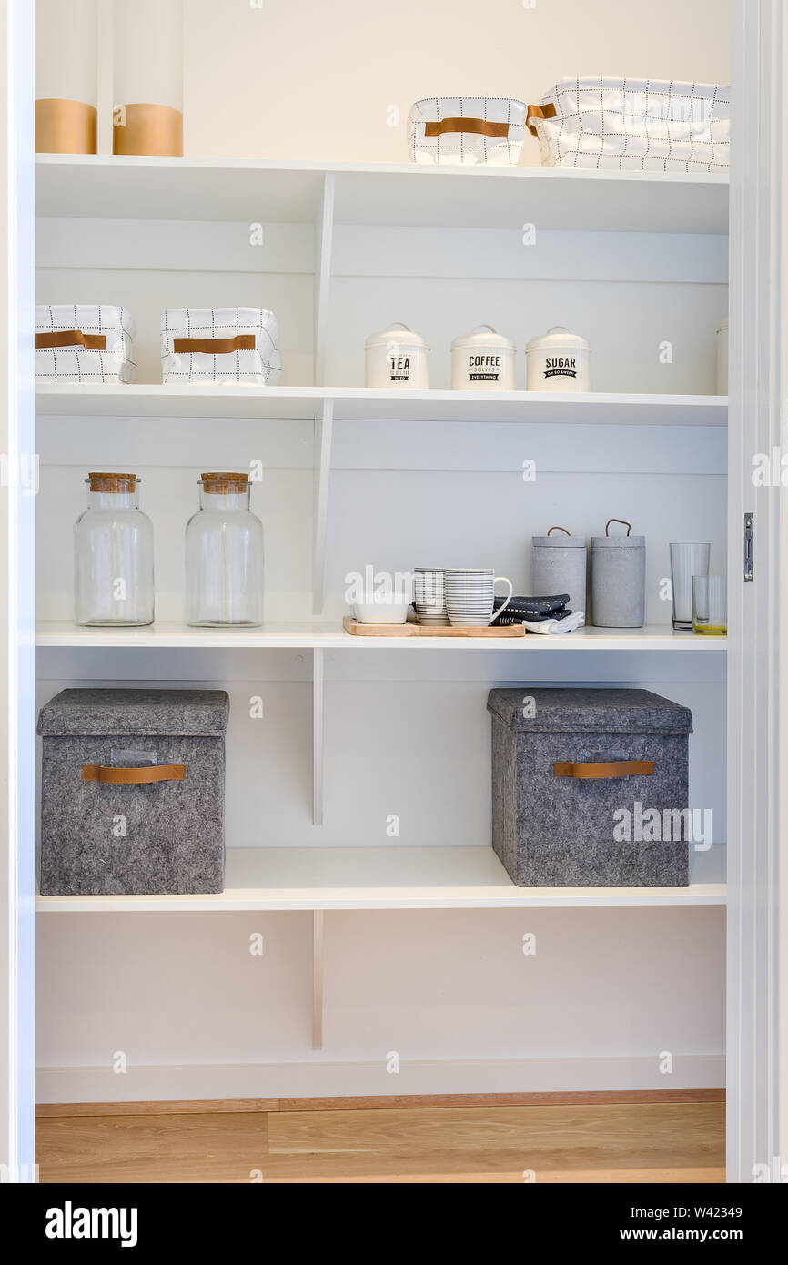 White wooden shelf included metal boxes and mugs with glass bottles ...