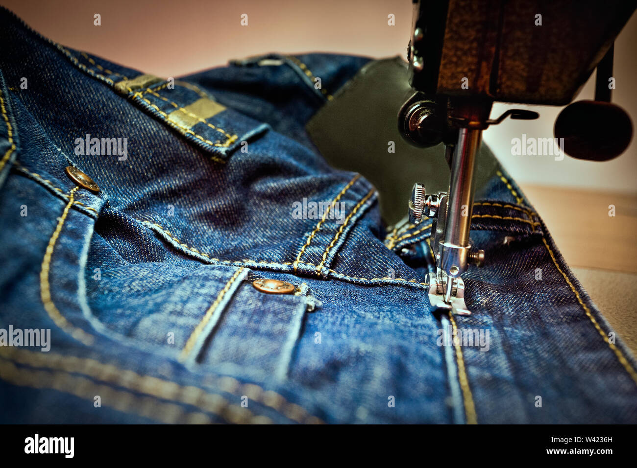 Machine sewing a blue jean close up with buttons and yarn, thread under ...