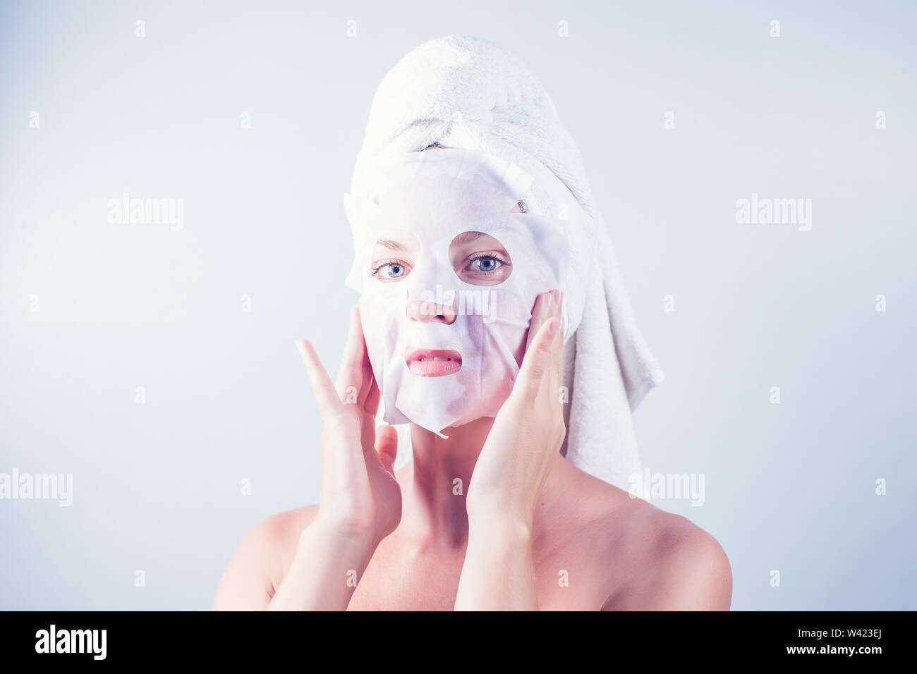 Young girl with facial mask looking at camera over white background ...