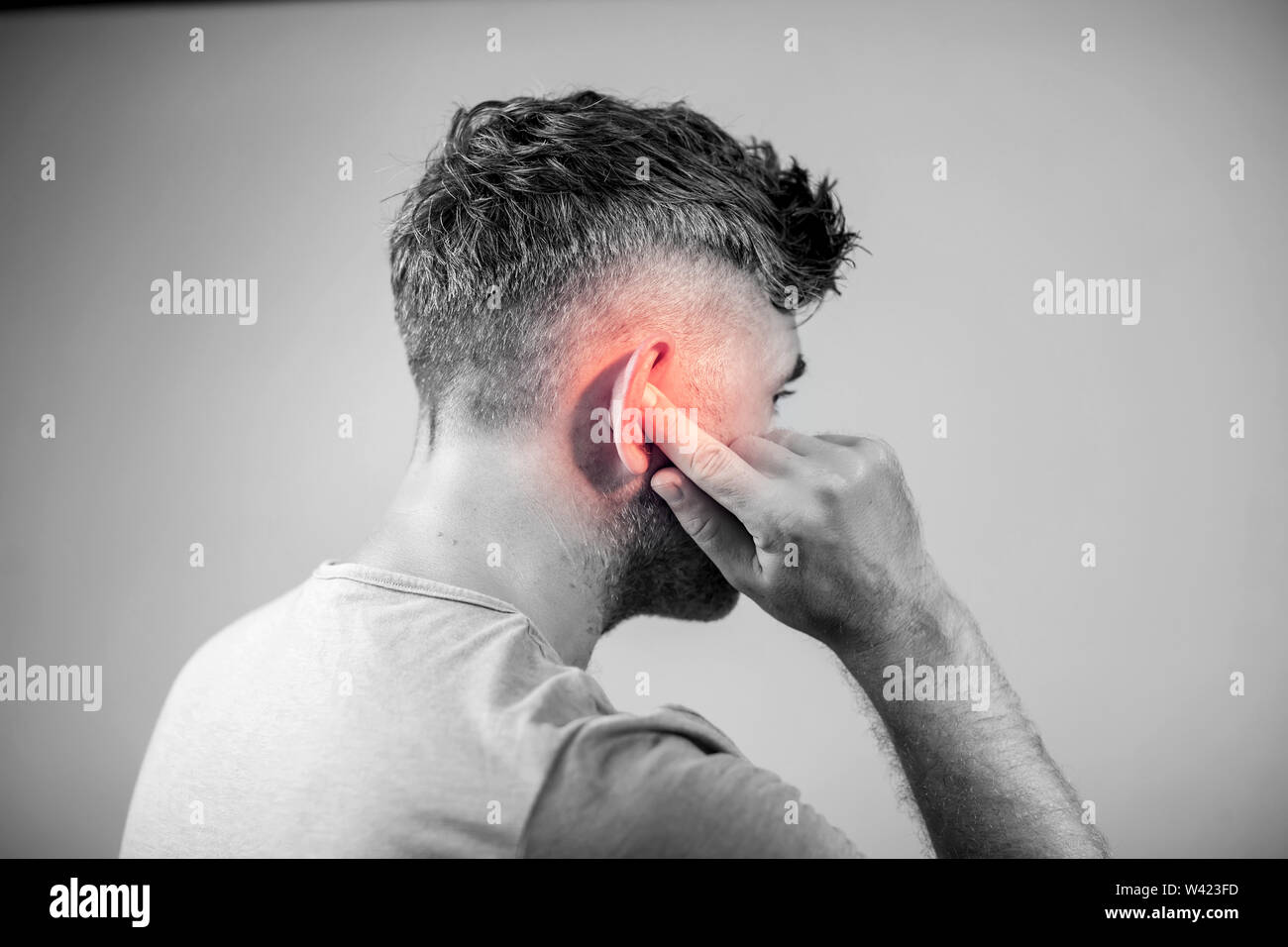 male having ear pain touching his painful head isolated on gray ...