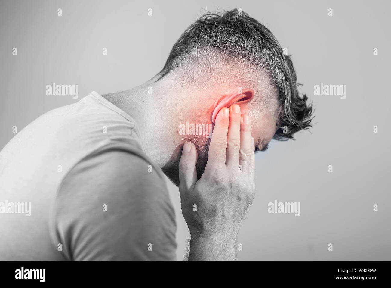 male having ear pain touching his painful head isolated on gray ...