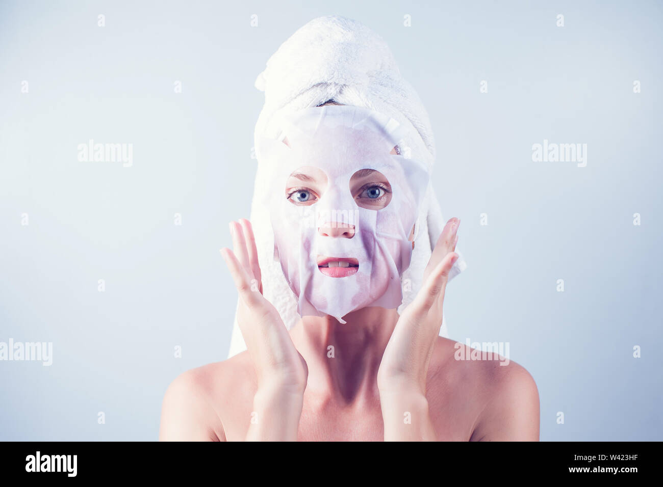 Young girl with facial mask looking at camera over white background ...