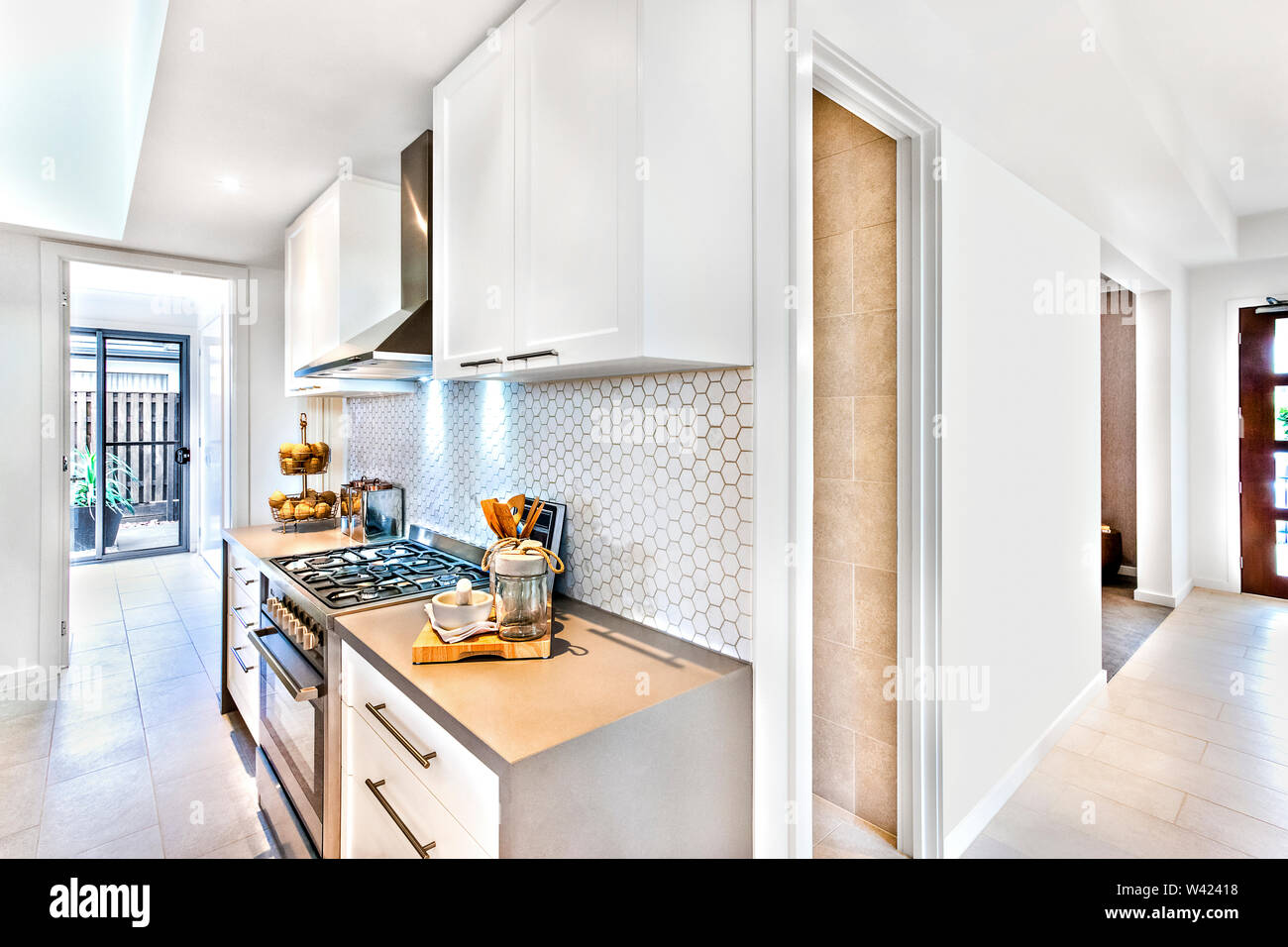 Modern kitchen with oven and stove next to hallway to a door and ...
