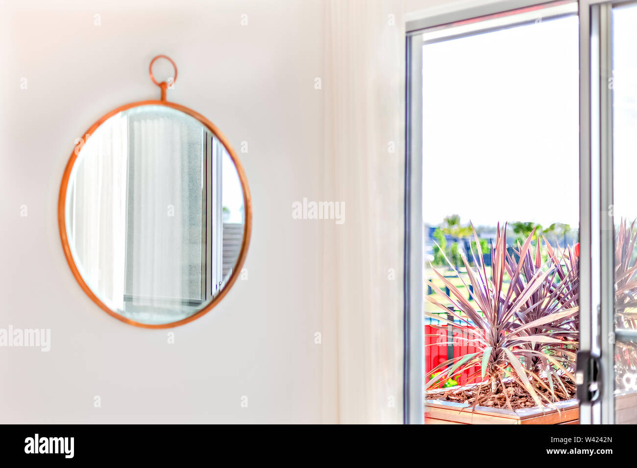 Circle shape mirror with a wooden frame on the wall near the curtain ...