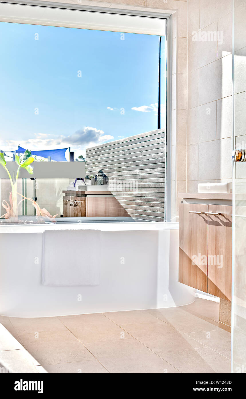 Bathtub and glass window of a modern bathroom illuminated by sunlight ...