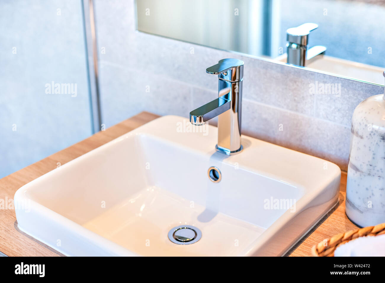 Closeup of a silver taps and ceramic sink in a modern bathroom with a ...