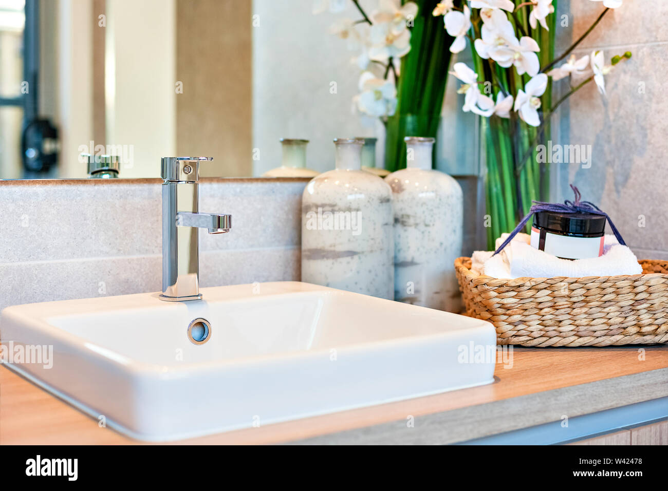 Silver taps and ceramic sink near perfume bottles with towels under ...