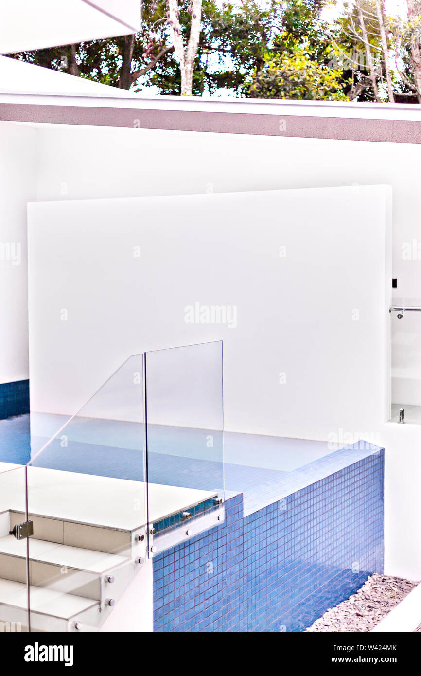 Blue water poolside with white walls and stairs in an outdoor area of ...