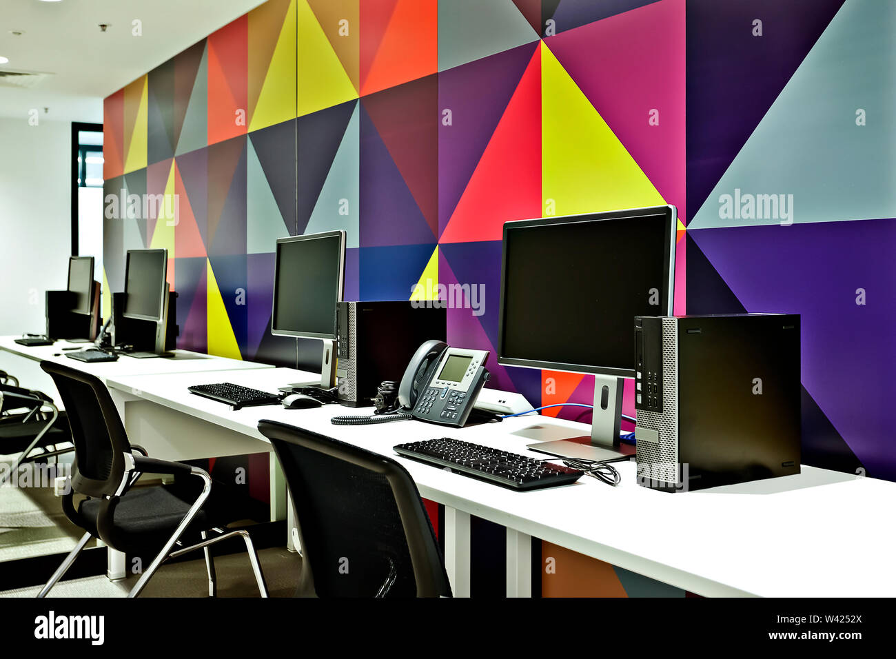 Workplace with computers, chairs and tables including telephones in ...