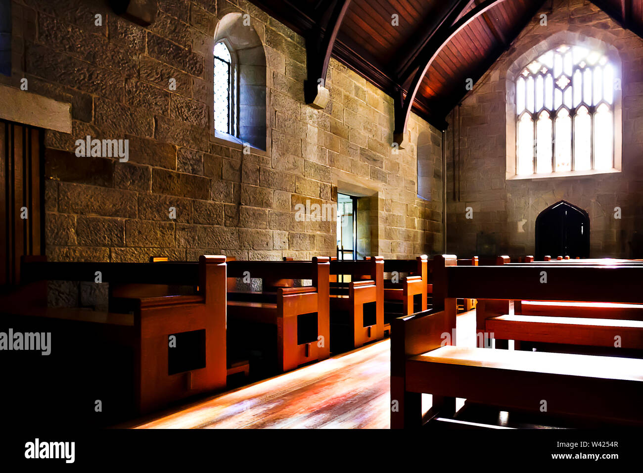 Old church architecture with stone walls and wooden benches brightened ...