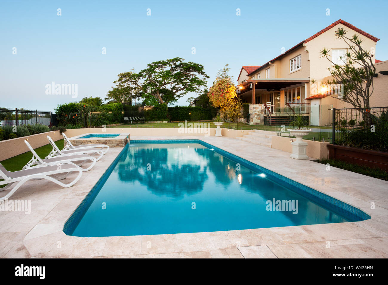 Light blue water swimming pool of a luxurious mansion with chairs ...
