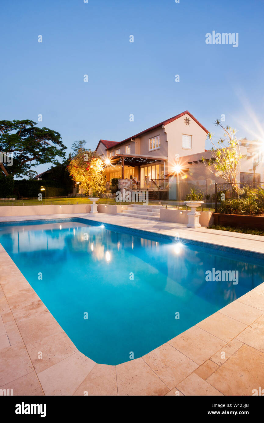 Modern swimming pool with a house or hotel at night with lights ...