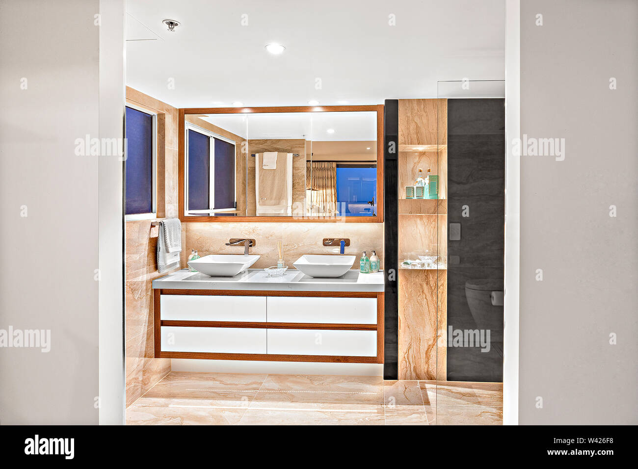 A sleek bathroom featuring a large mirror, vanity basins, and tiled ...