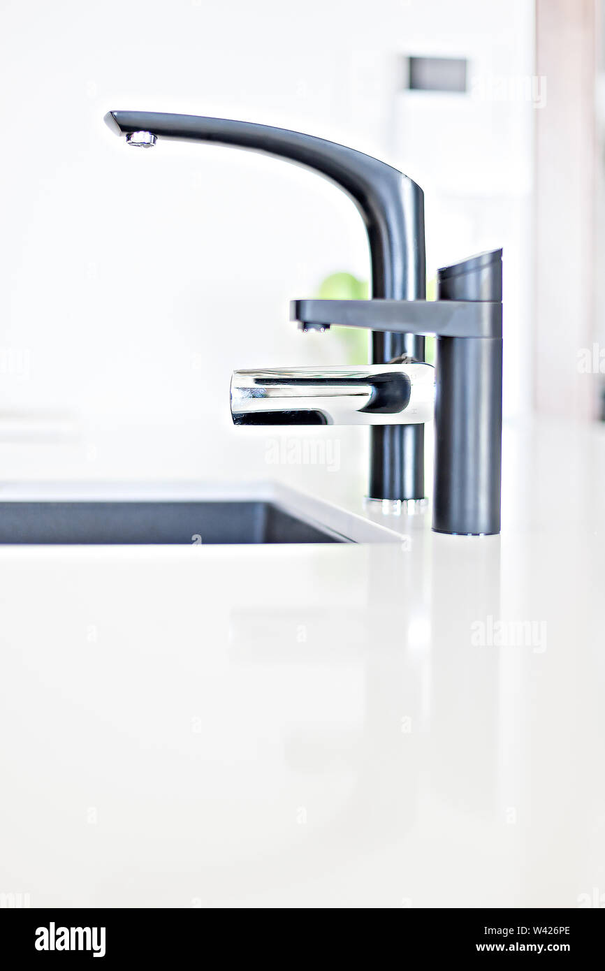 Sleek basing taps on the kitchen counter basin Stock Photo - Alamy