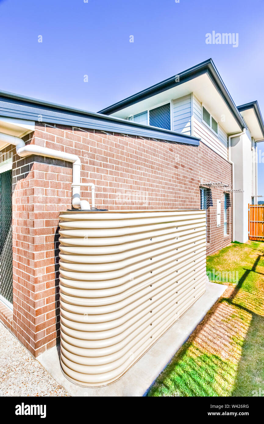 Water tank attached to wall in classic house, green grass on ground ...